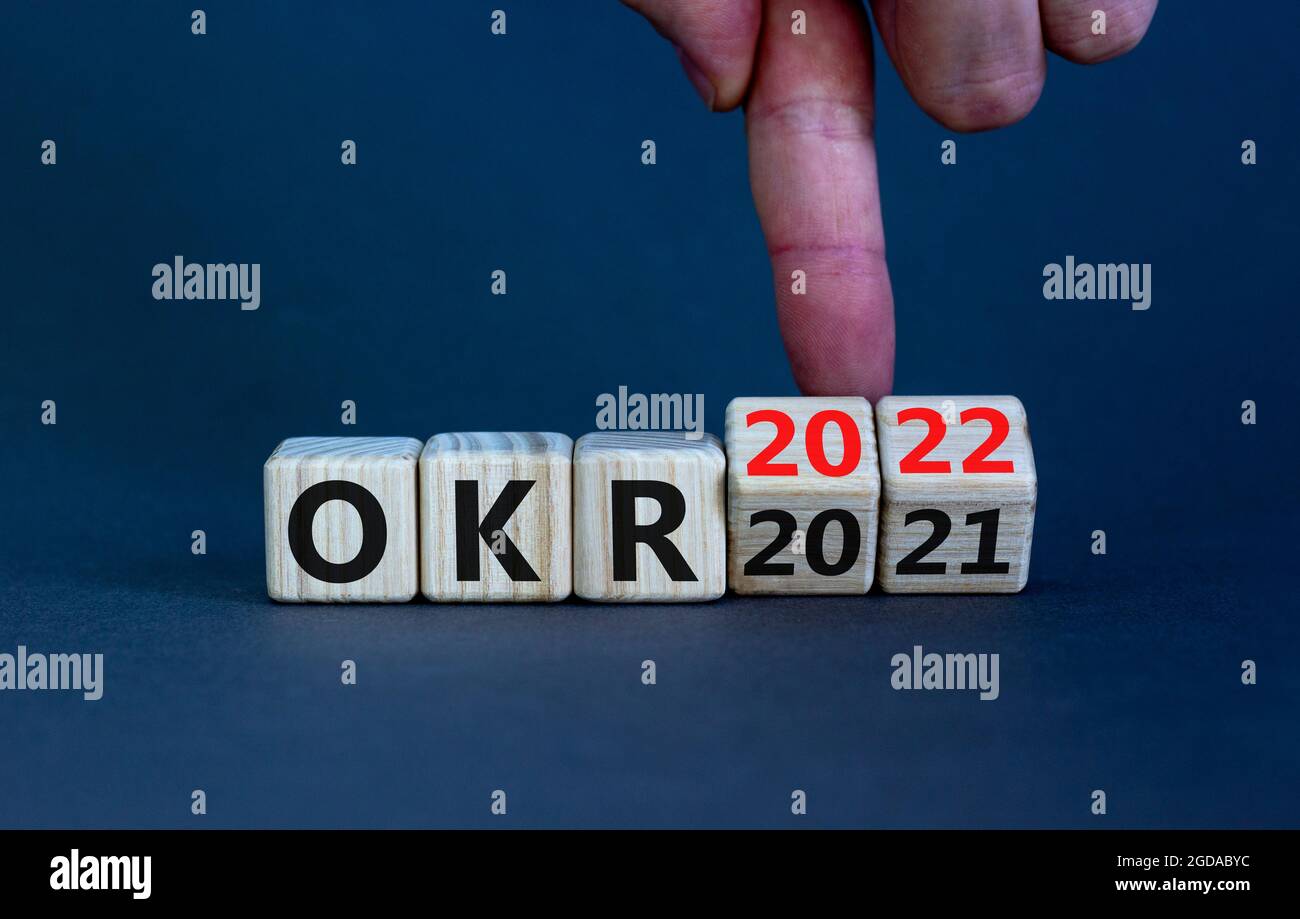 OKR, objectives and key results symbol. Businessman turns cubes with words 'OKR 2021' and 'OKR ...