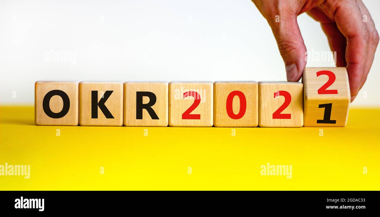 OKR, objectives and key results symbol. Businessman turns cubes with words 'OKR 2021' and 'OKR ...