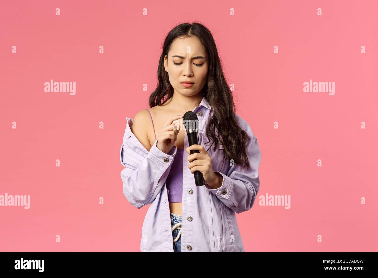 Portrait of awkward silly asian girl tap microphone as checking is it ...