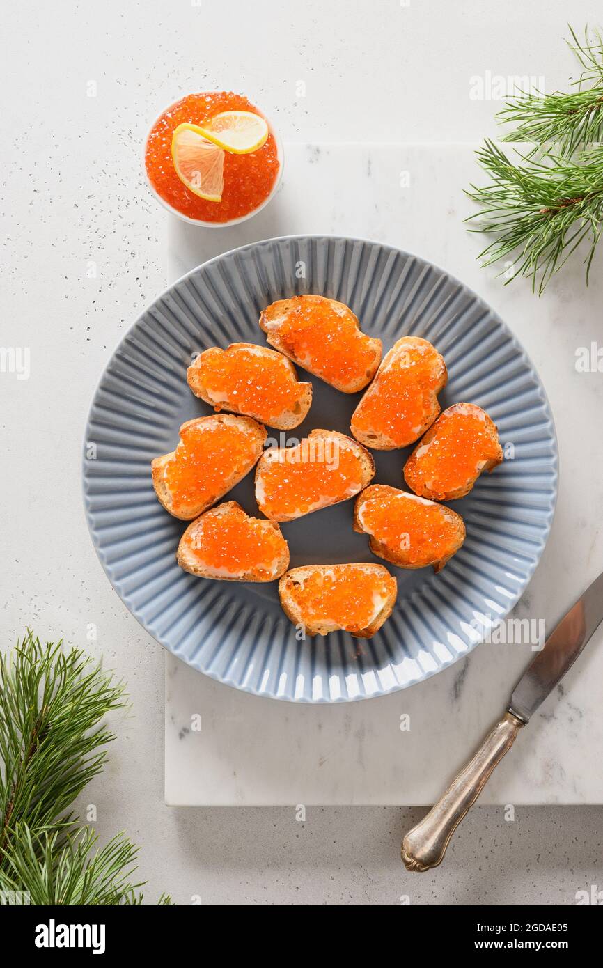 Russian appetizer canape with red caviar on ciabatta on a white marble ...