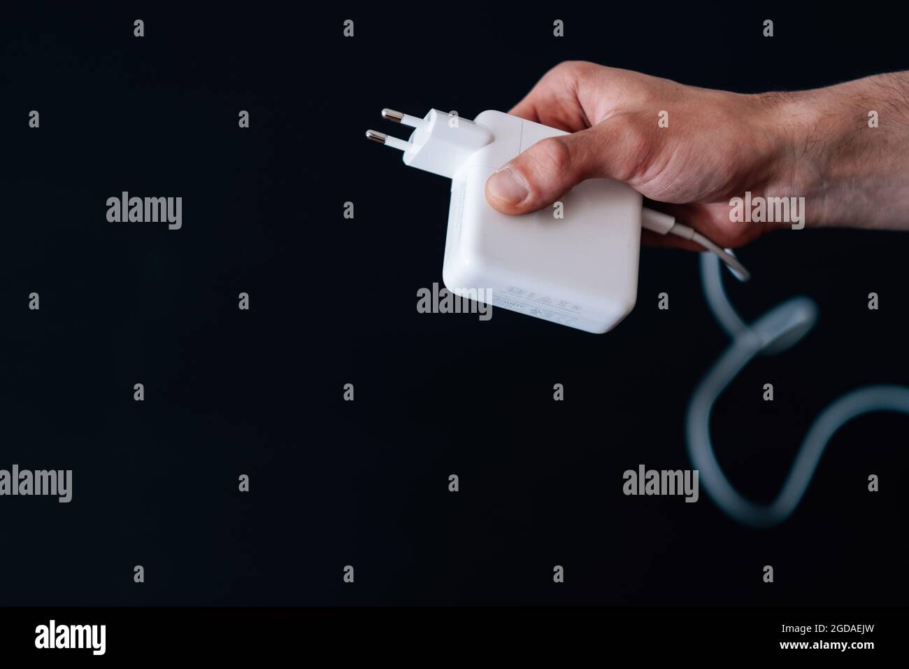 Closeup shot of a male hand holding a white charger on the black ...