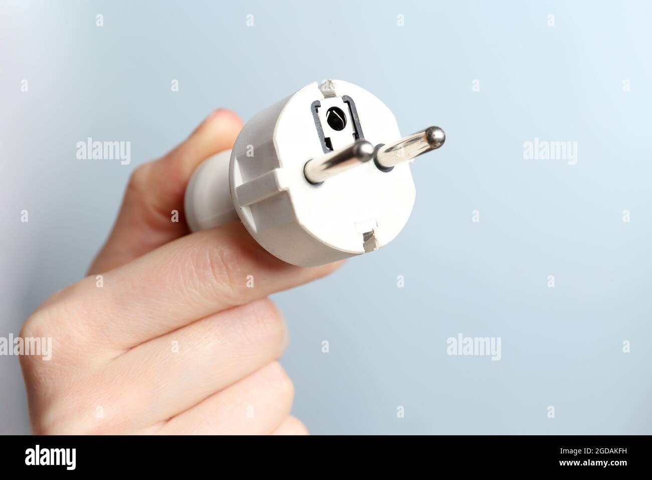 Hand holding electric plug on blue background Stock Photo - Alamy