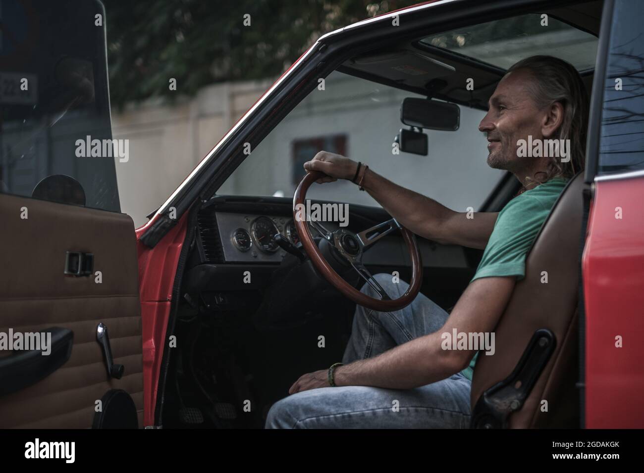 Portrait of mature handsome man sitting in red old style car and ...
