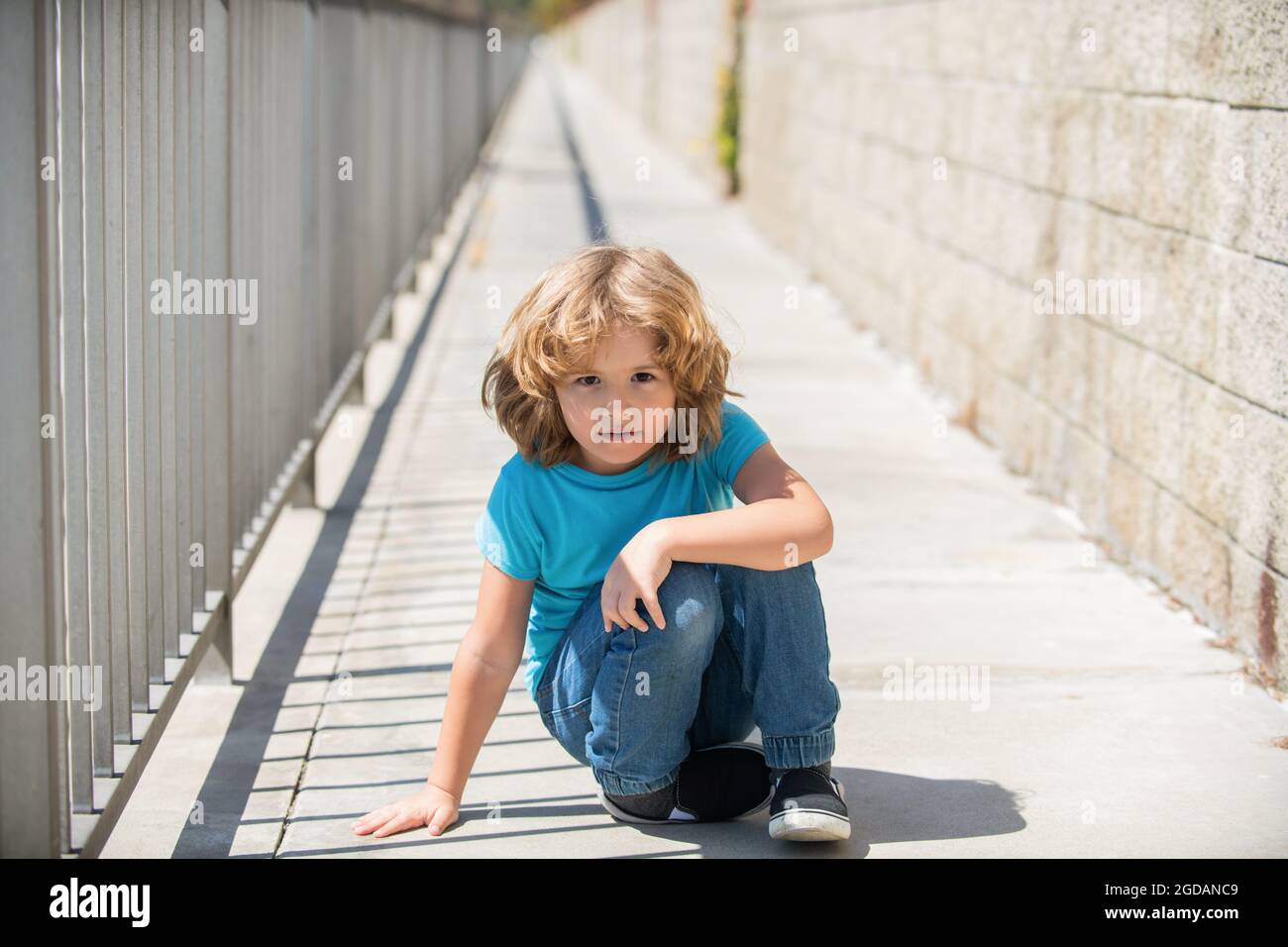 Boy kid take rest sitting down on promenade on summer outdoors, resting ...