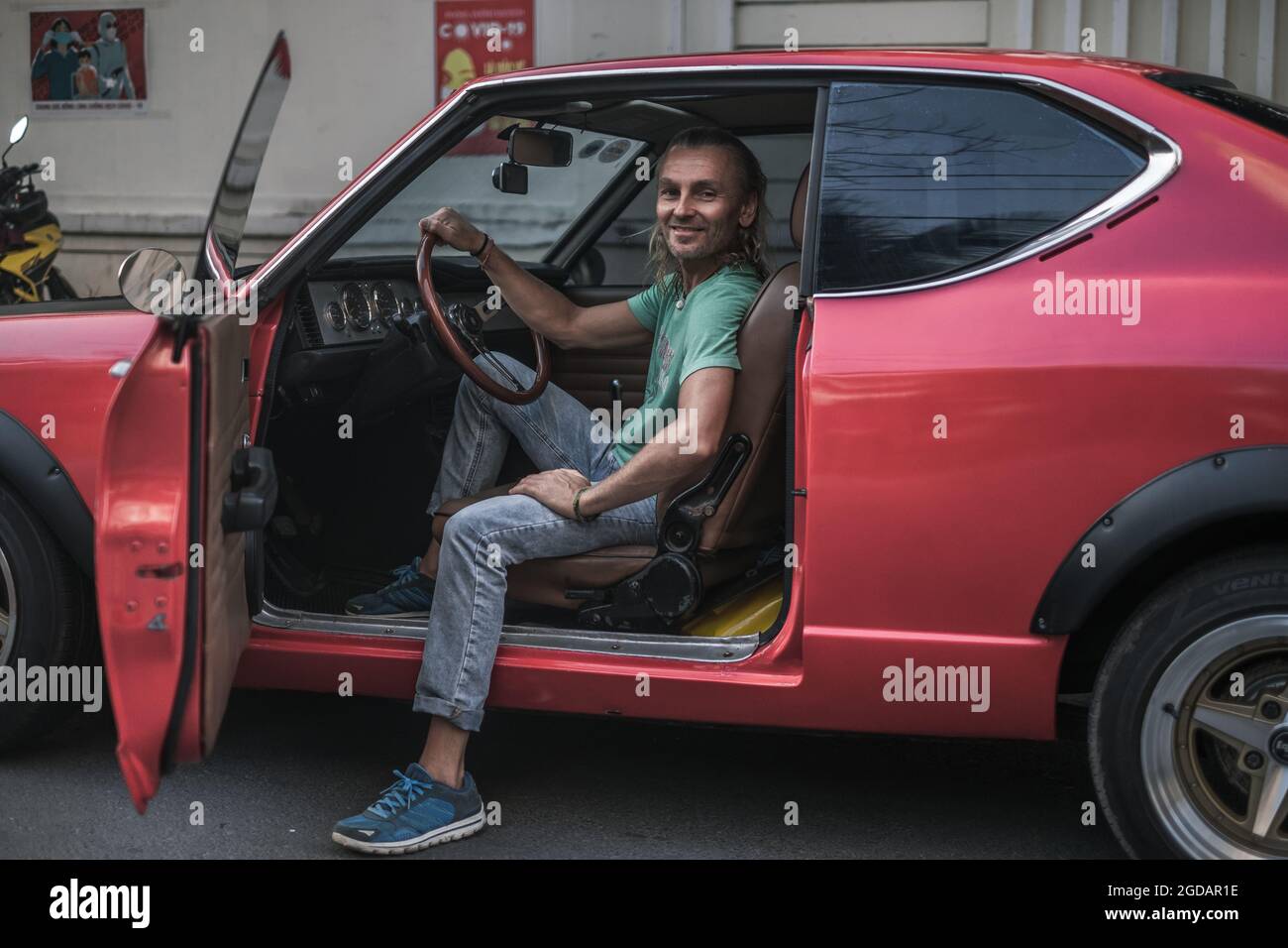 Mature handsome man sitting in red old style car, holding steering ...