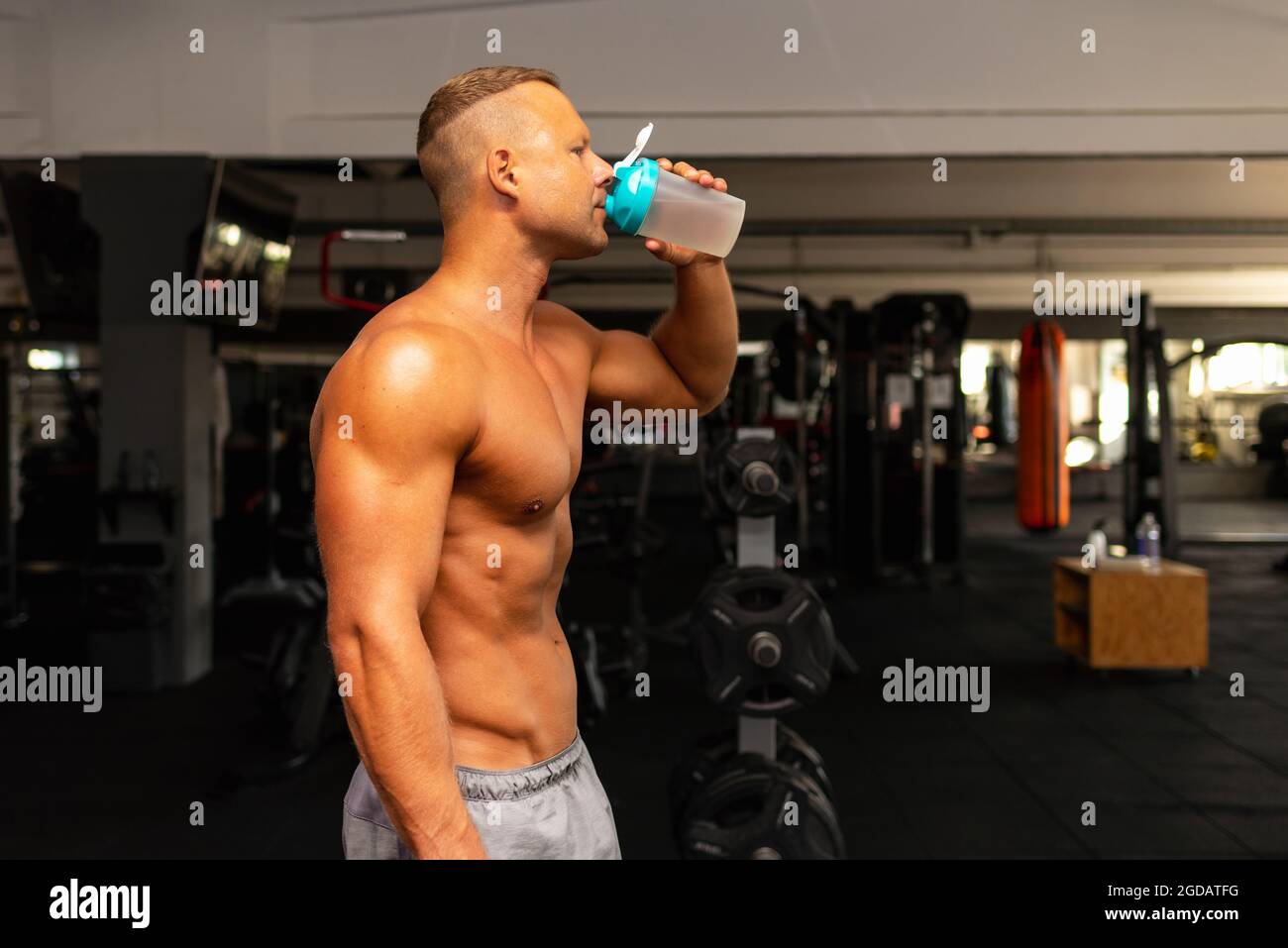Young caucasian man drinking water after exercise.man in the gym ...