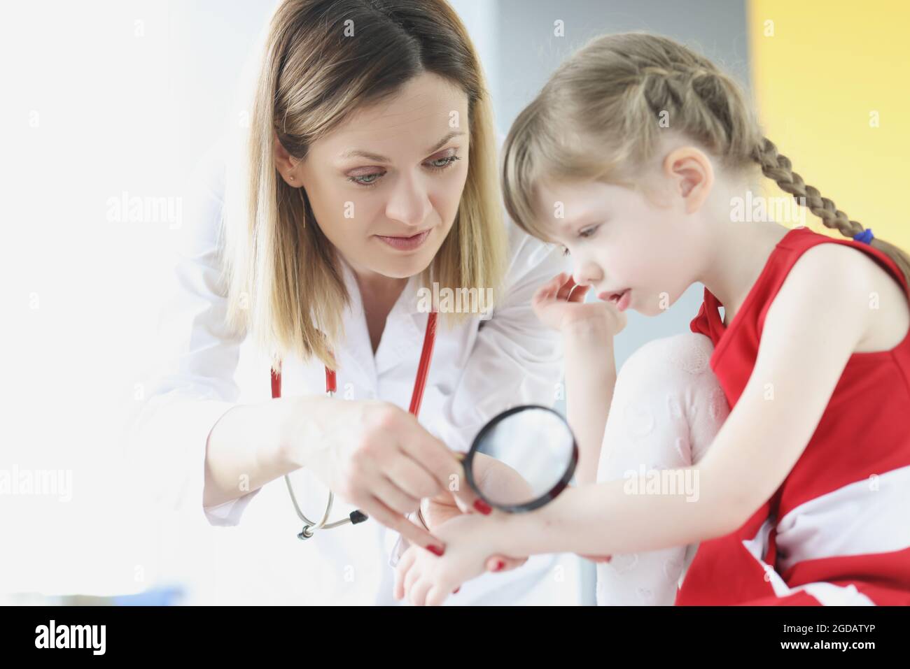 Doctor examining skin on hand of little girl using magnifying glass in ...