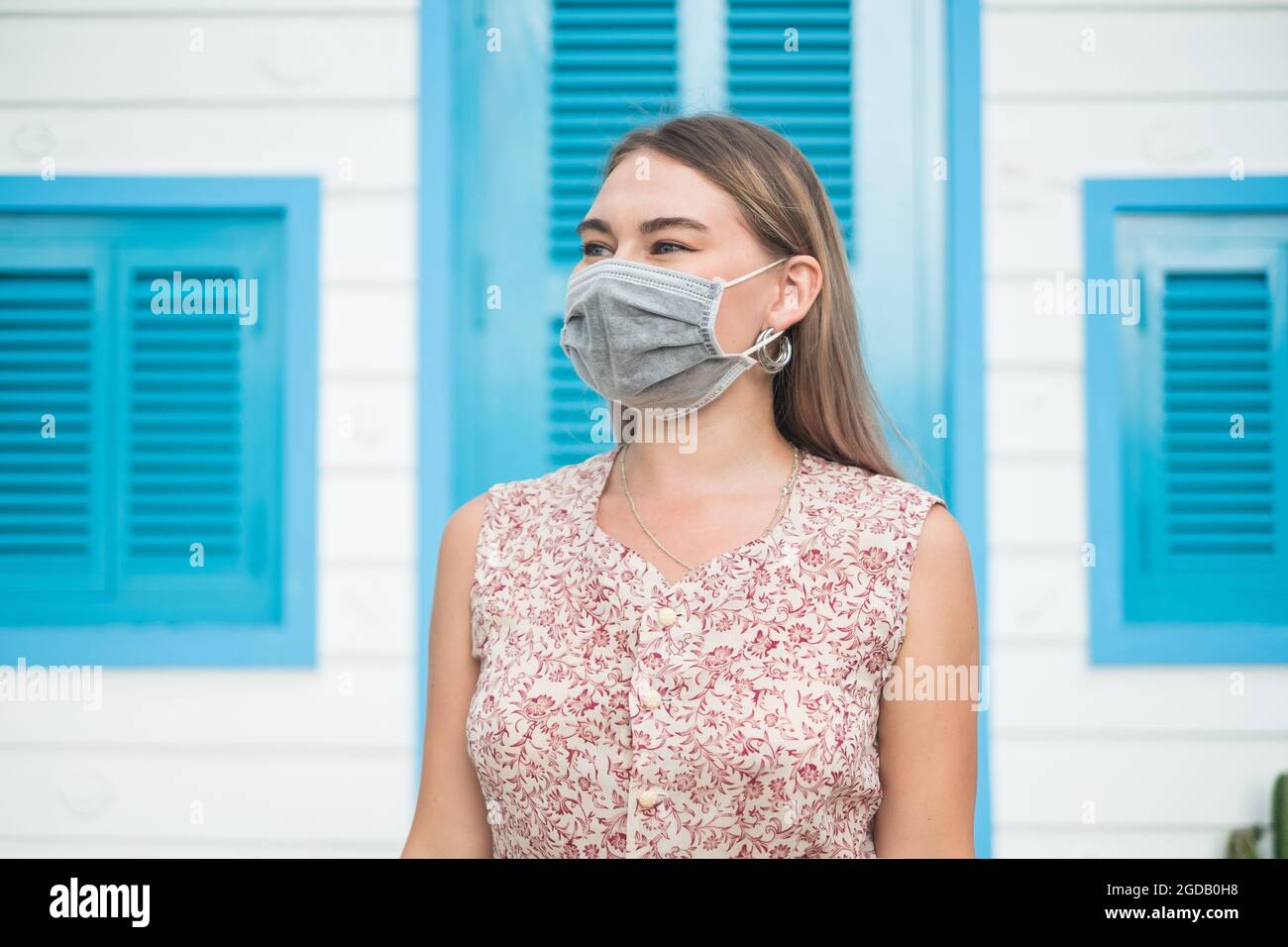 Cheerful caucasian young woman wearing disposable face mask. Protection ...