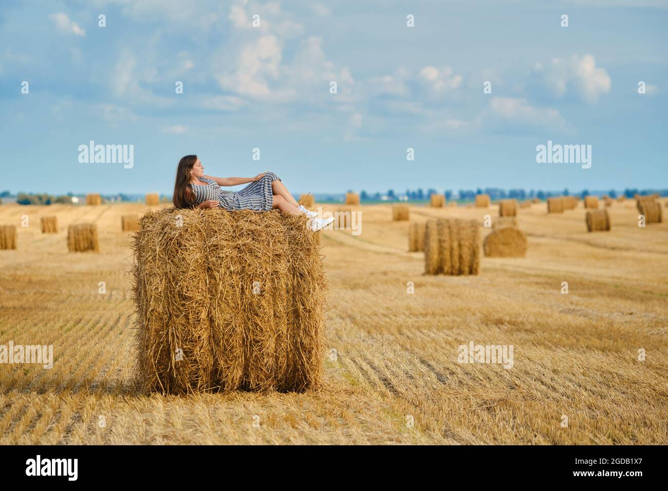 Calm young woman laying on the top of stack of straw on the field Stock ...