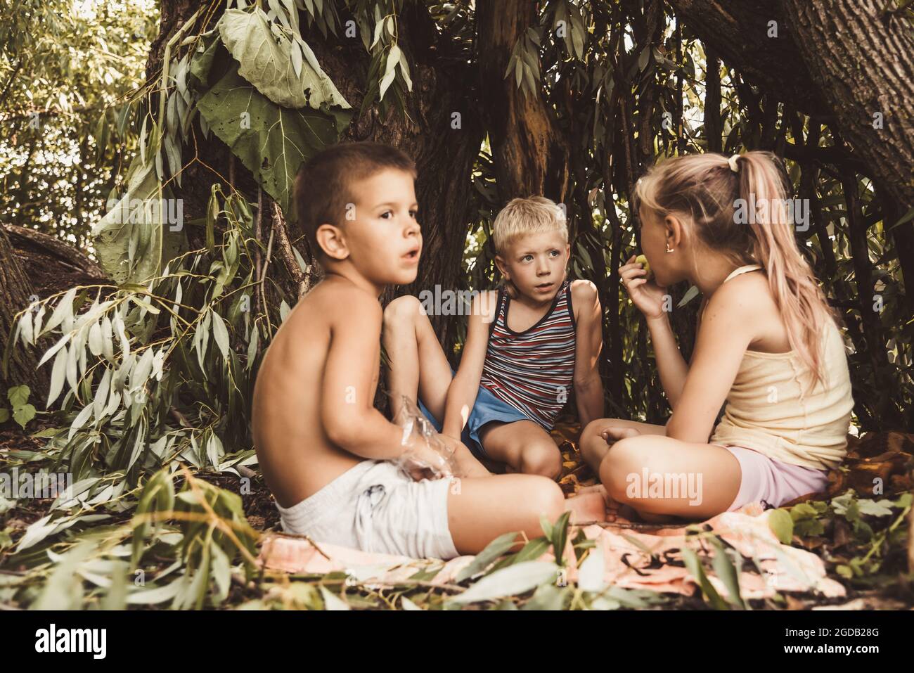 Three children play in a hut which they themselves have built from ...