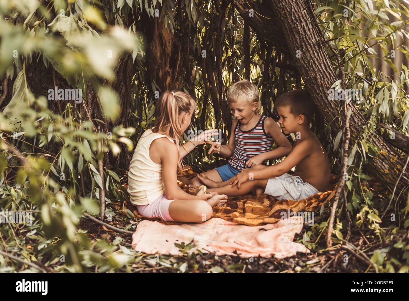 Three children play in a hut which they themselves have built from ...