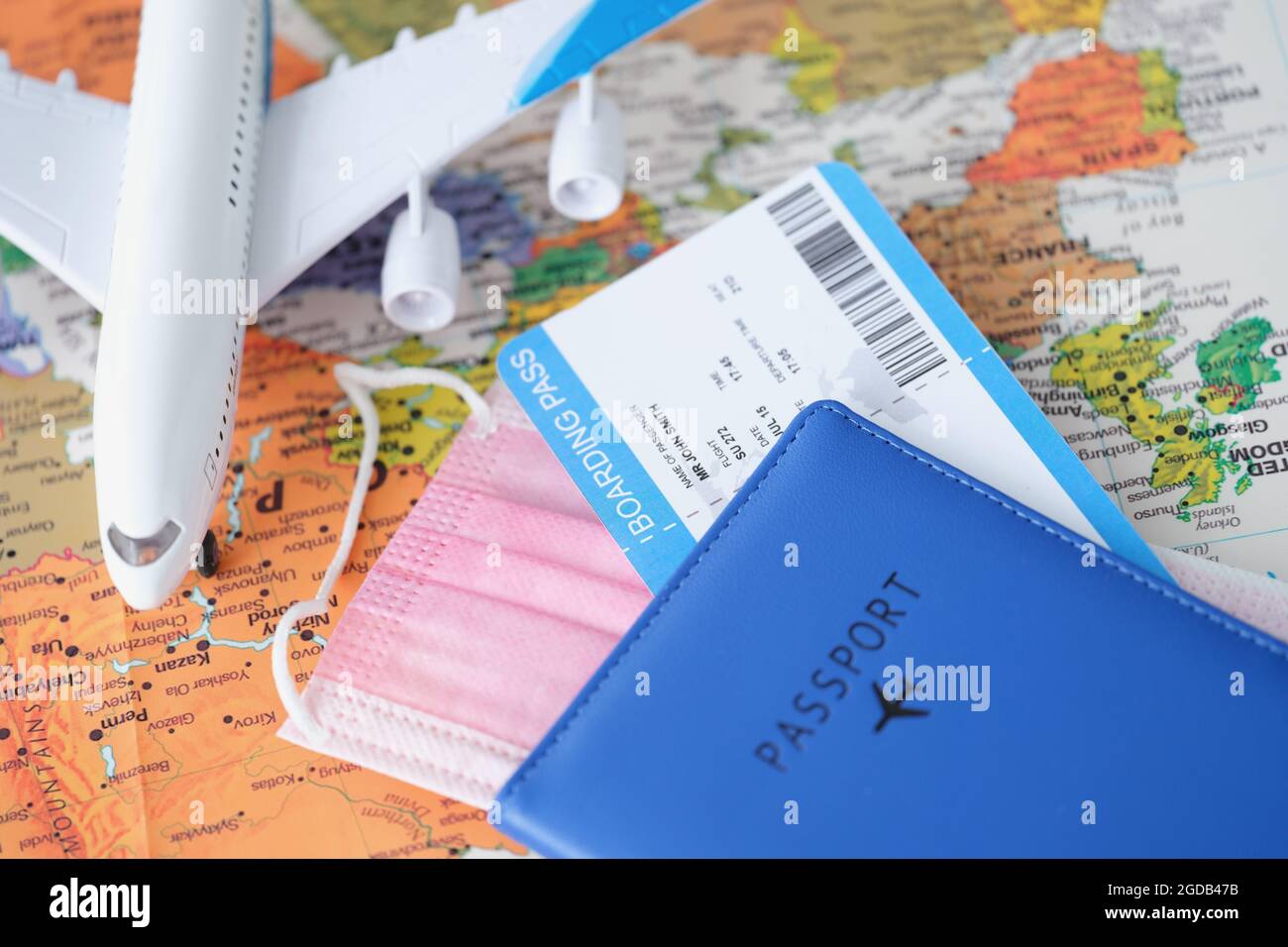 Passport with boarding pass and protective medical mask lying on world ...