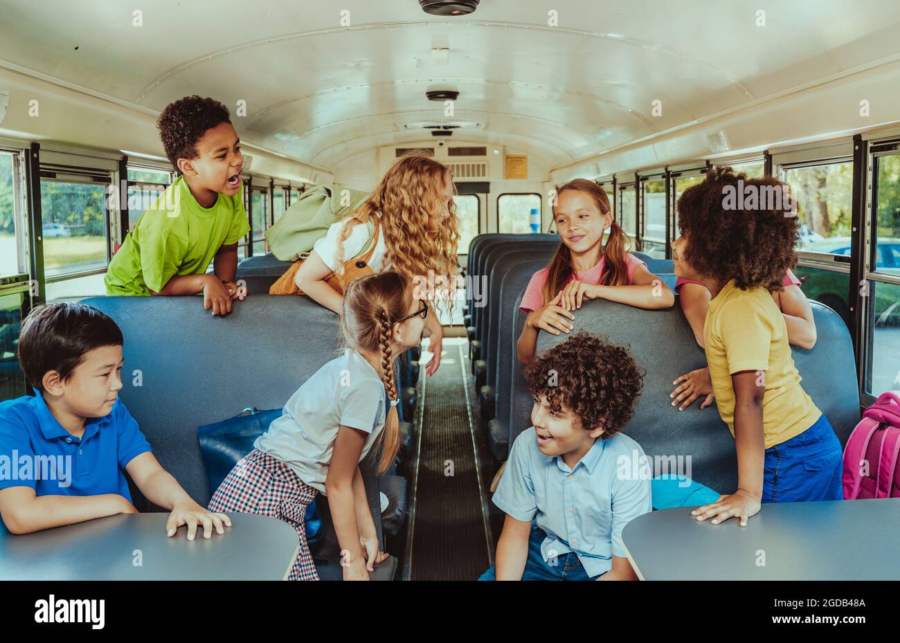 Group of young students attending primary school on a yellow school bus ...
