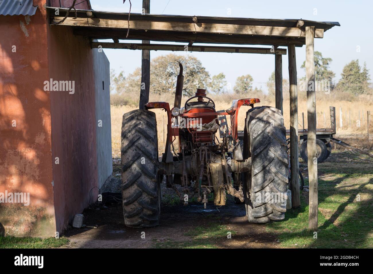 Closeup of an old rusty tractor parked under the wooden roof near the ...