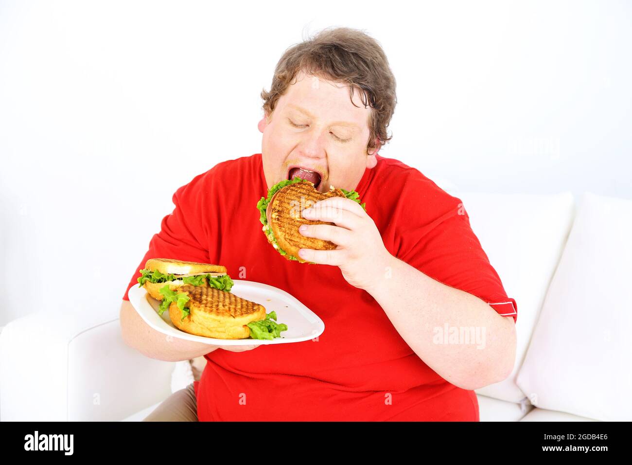 Fat man eating tasty sandwich on home interior background Stock Photo ...
