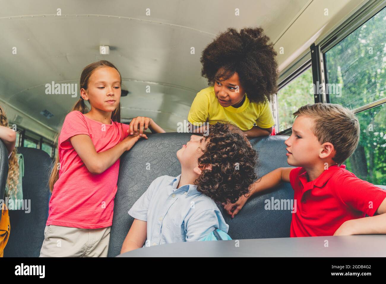 Group of young students attending primary school on a yellow school bus ...