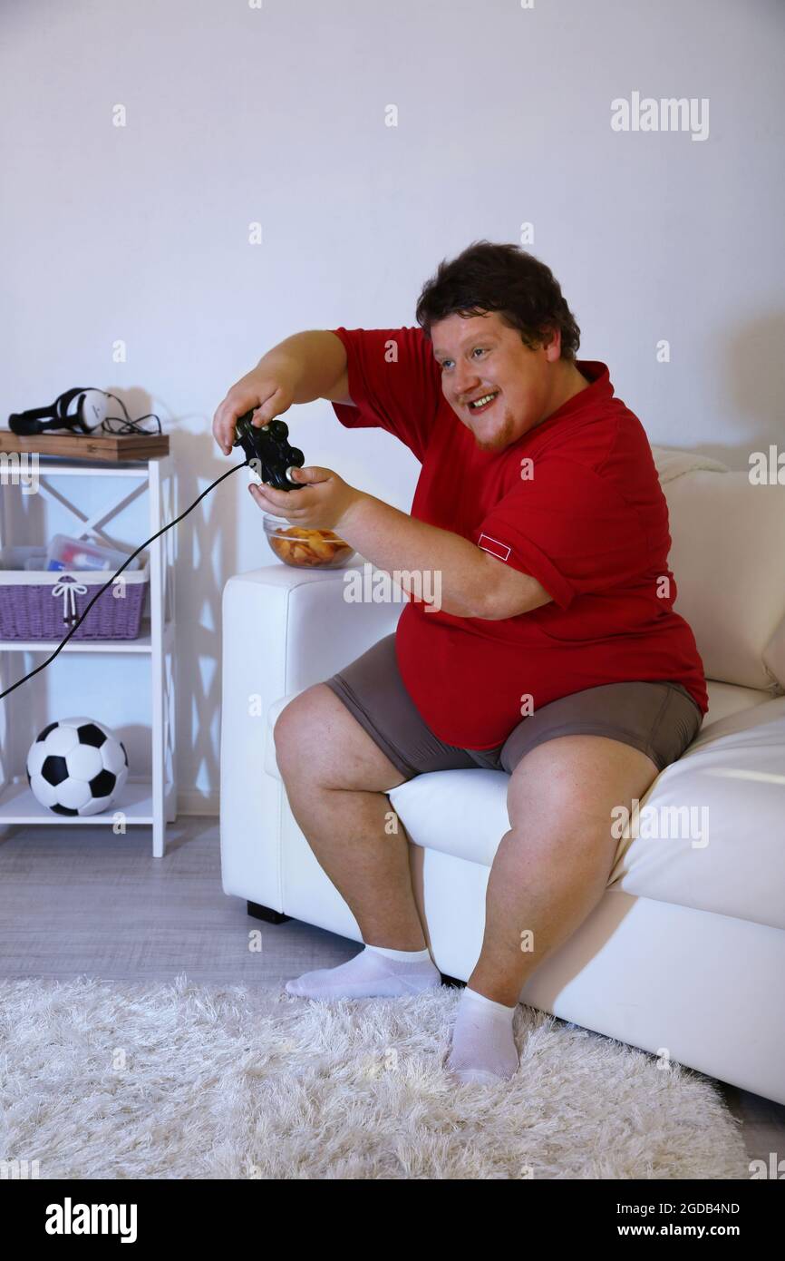Fat man playing video games on home interior background Stock Photo - Alamy