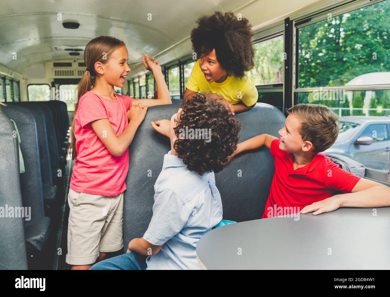 Group of young students attending primary school on a yellow school bus ...