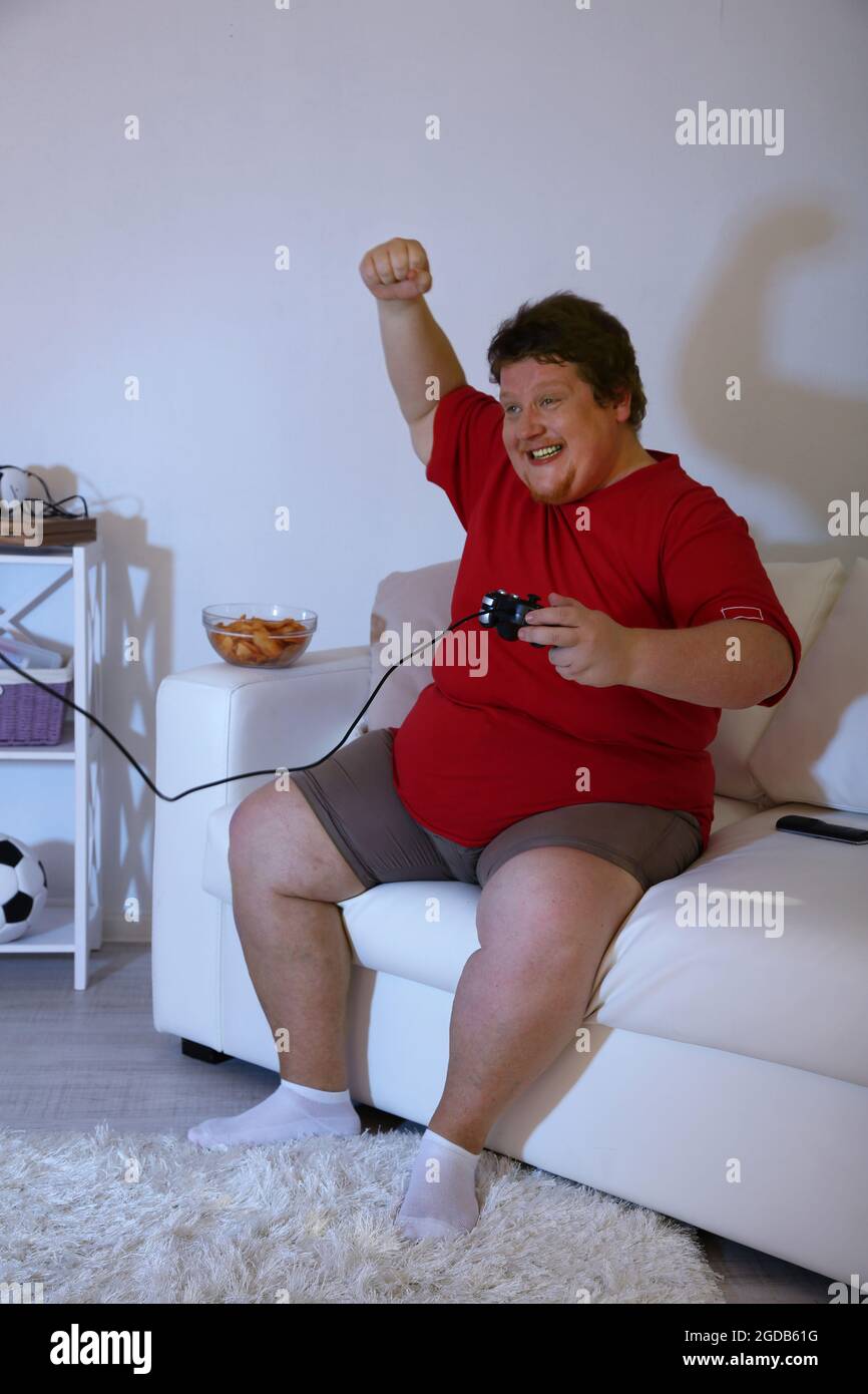 Fat man playing video games on home interior background Stock Photo - Alamy
