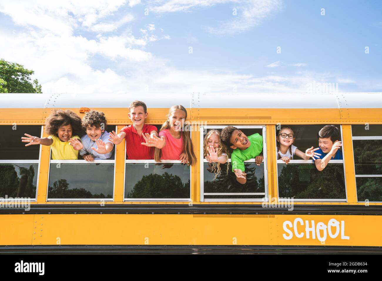 Group of young students attending primary school on a yellow school bus ...
