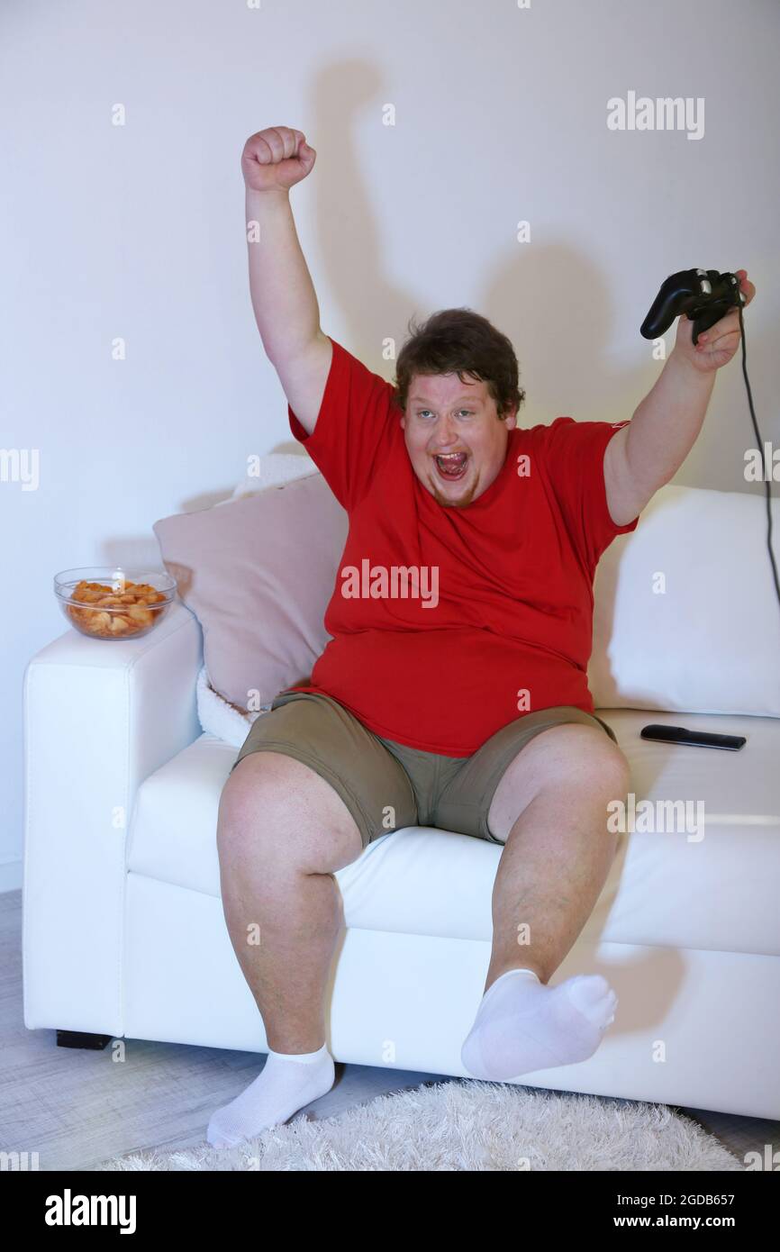 Fat man playing video games on home interior background Stock Photo - Alamy