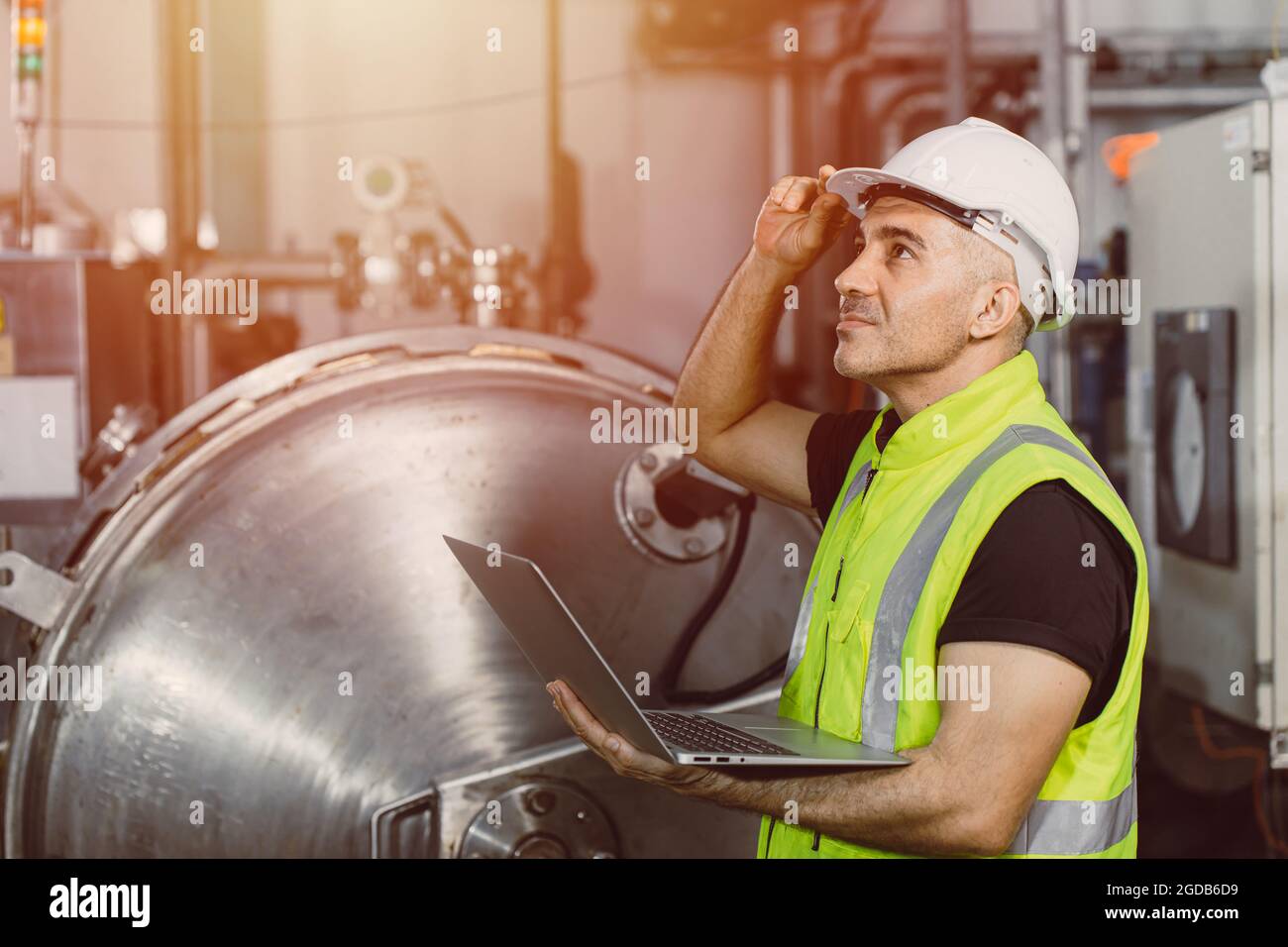 Engineer worker working in plant factory boiler service using laptop to ...