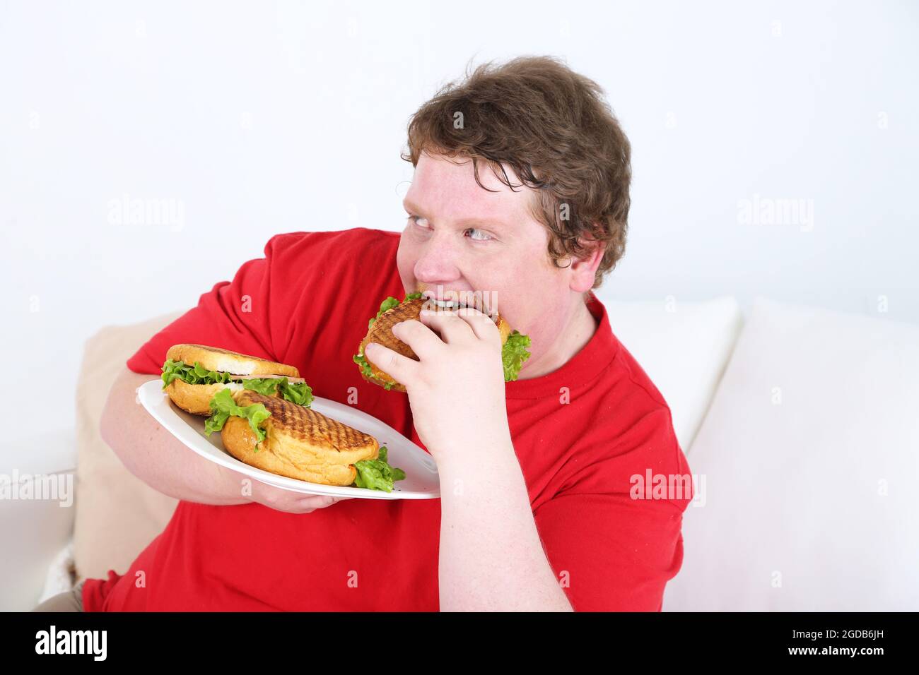 Fat man eating tasty sandwich on home interior background Stock Photo ...