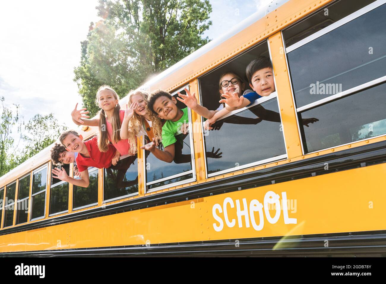 Group of young students attending primary school on a yellow school bus ...