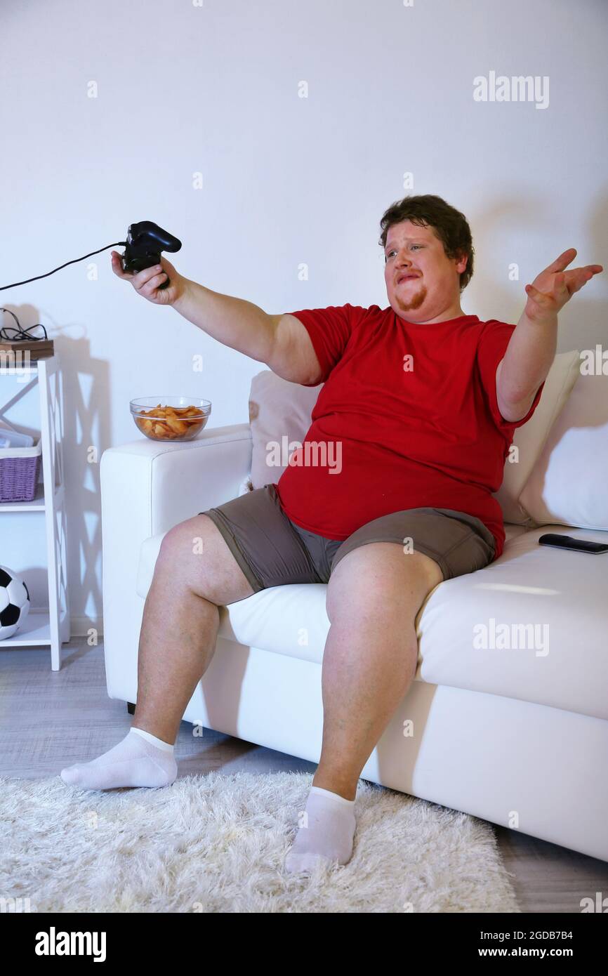 Fat man playing video games on home interior background Stock Photo - Alamy