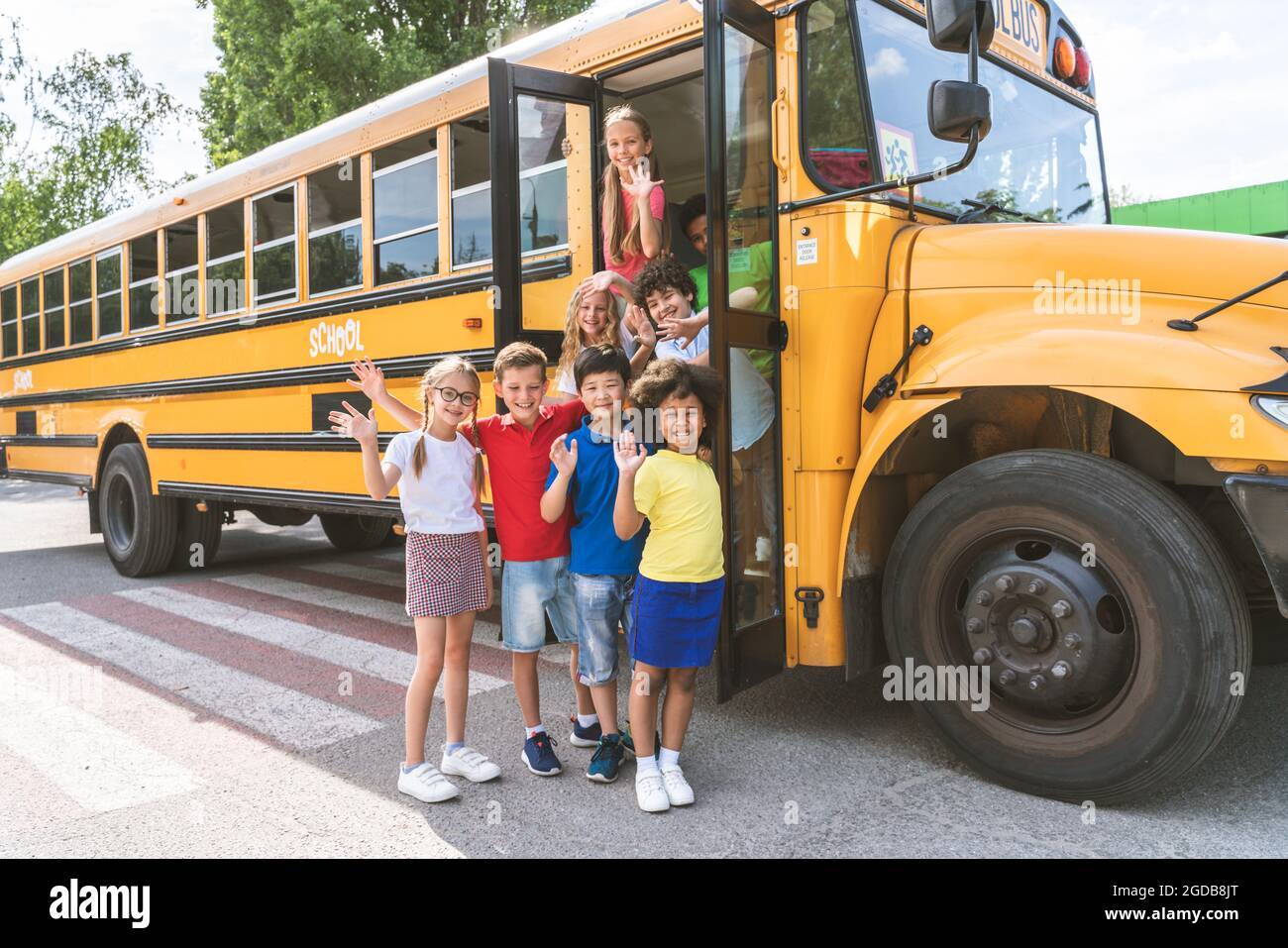 Group of young students attending primary school on a yellow school bus ...