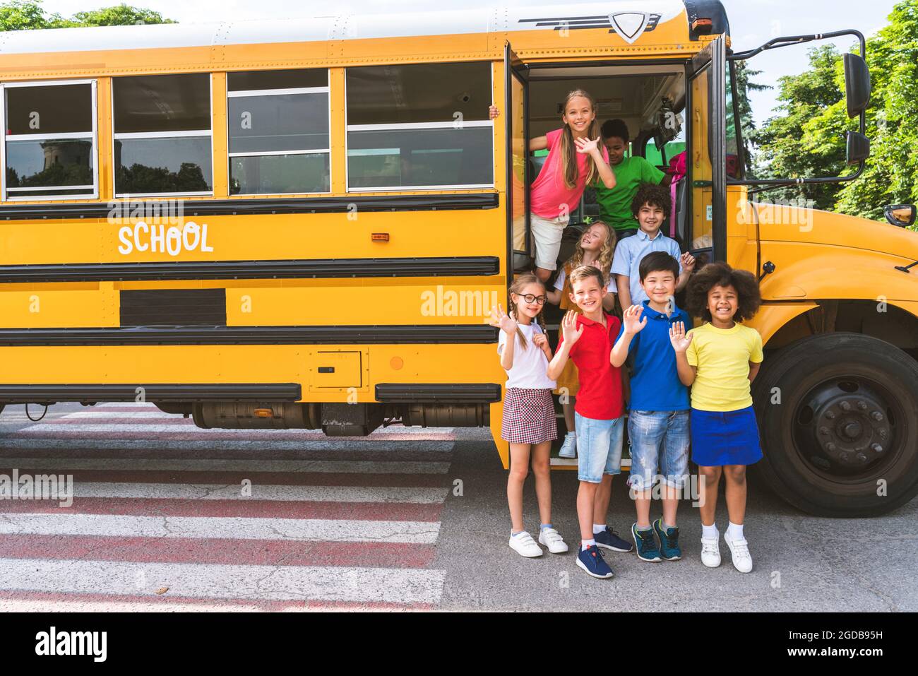 Group of young students attending primary school on a yellow school bus ...