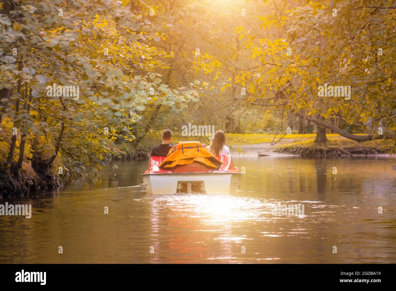 Couple in love in a catamaran, water bike in a park in autumn, sunset ...