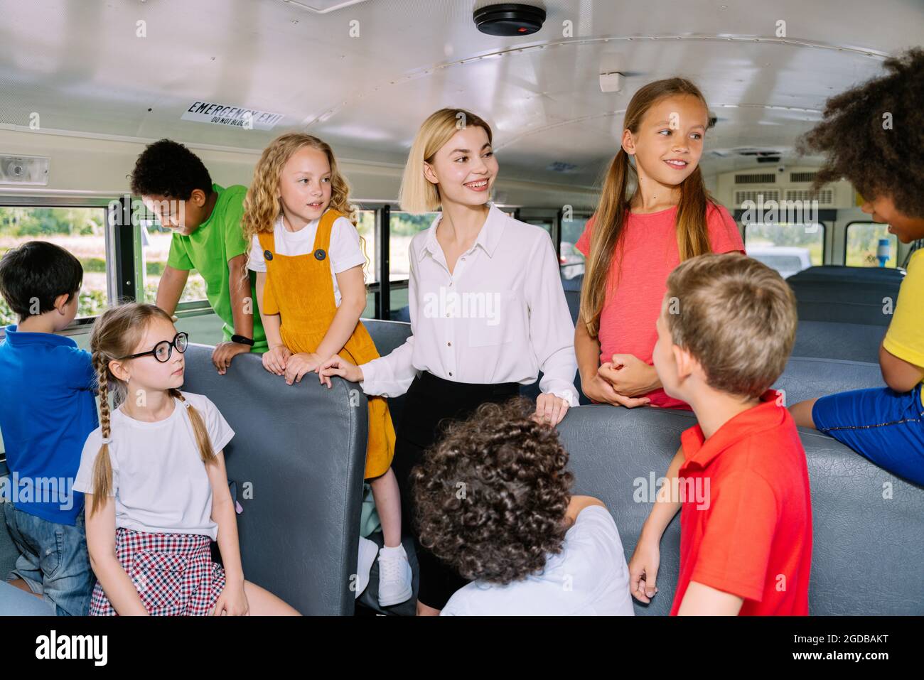 Group of young students attending primary school on a yellow school bus ...