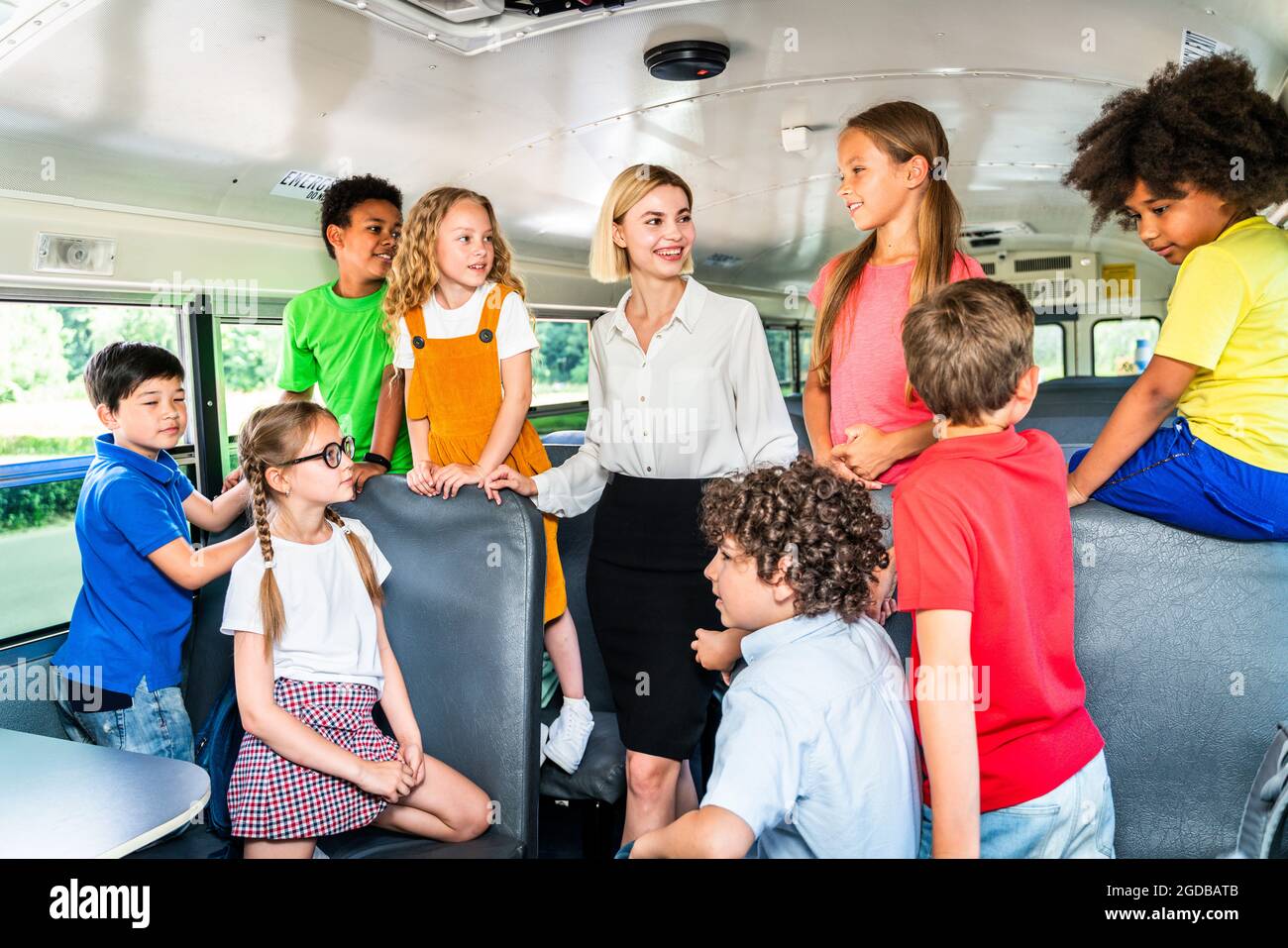Group of young students attending primary school on a yellow school bus ...