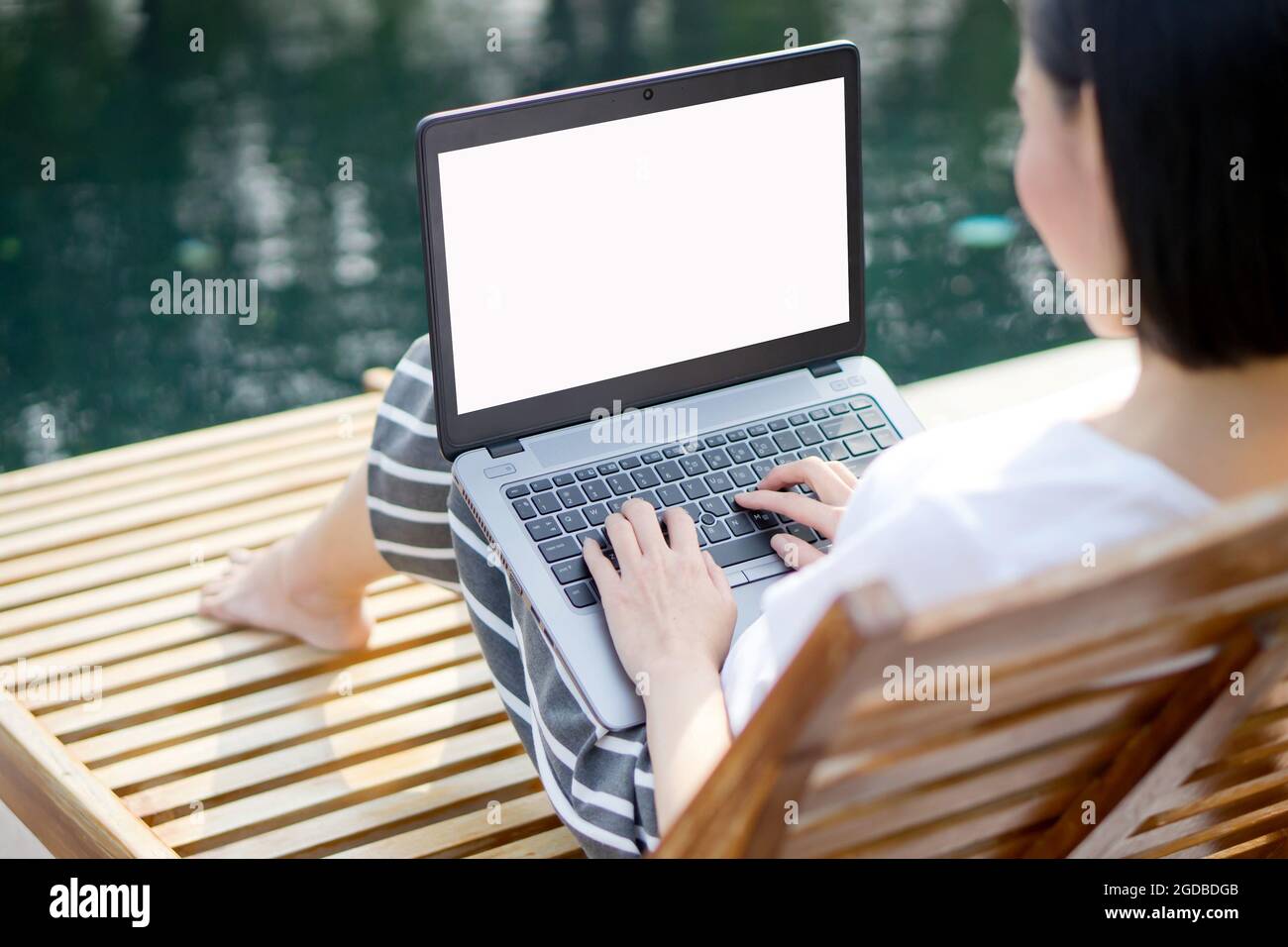 Woman working with laptop computer sitting at swimming pool Stock Photo ...