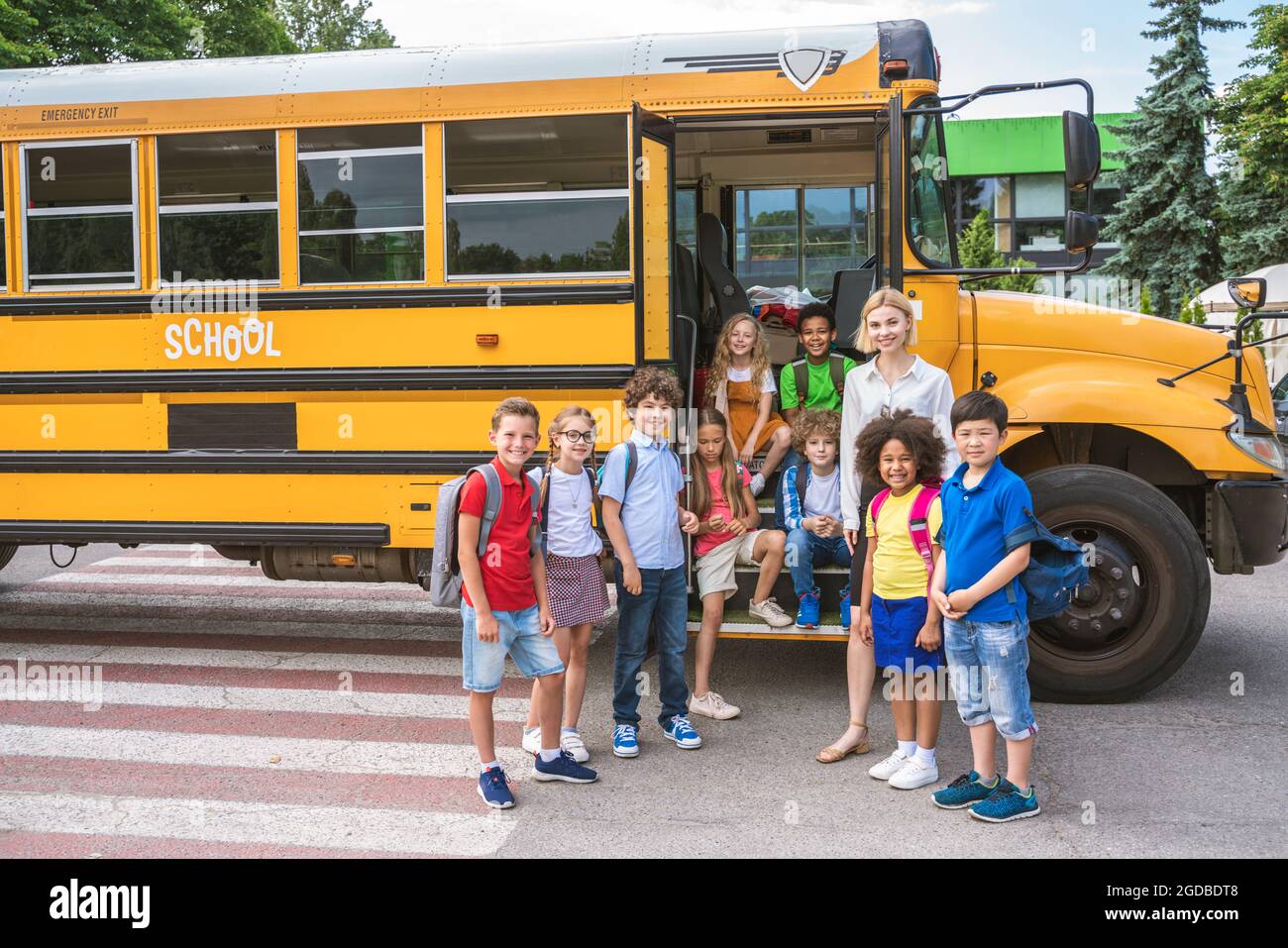 Group of young students attending primary school on a yellow school bus ...