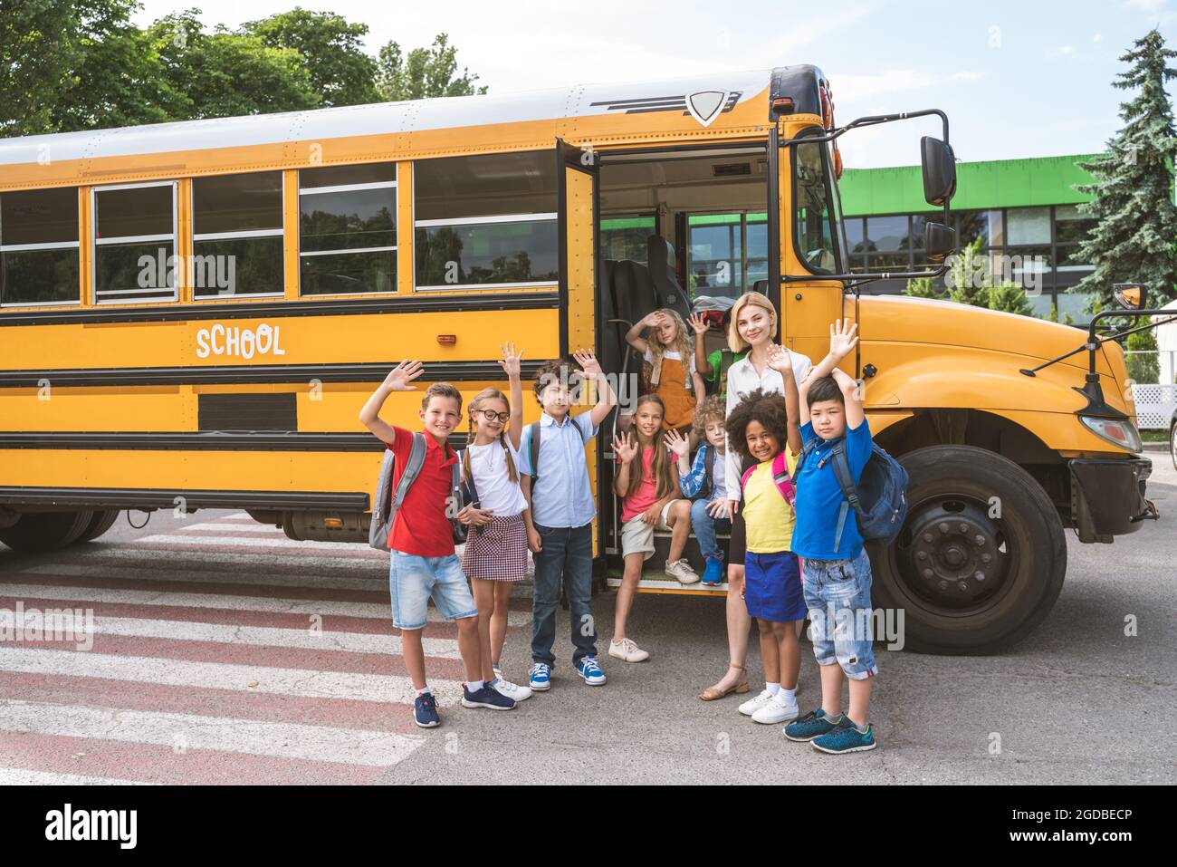 Group of young students attending primary school on a yellow school bus ...