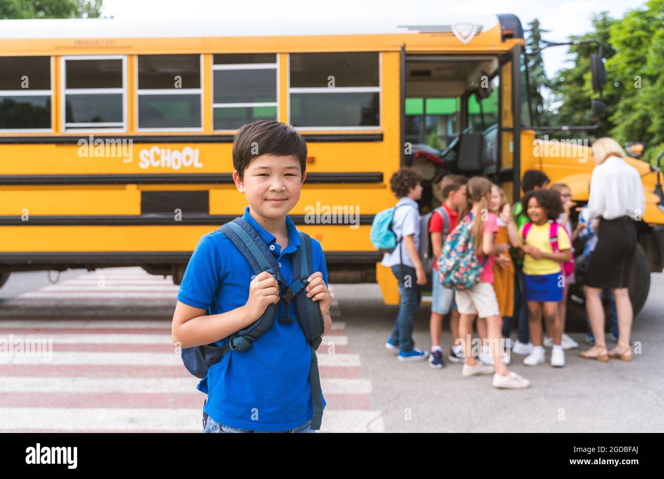 Group of young students attending primary school on a yellow school bus ...