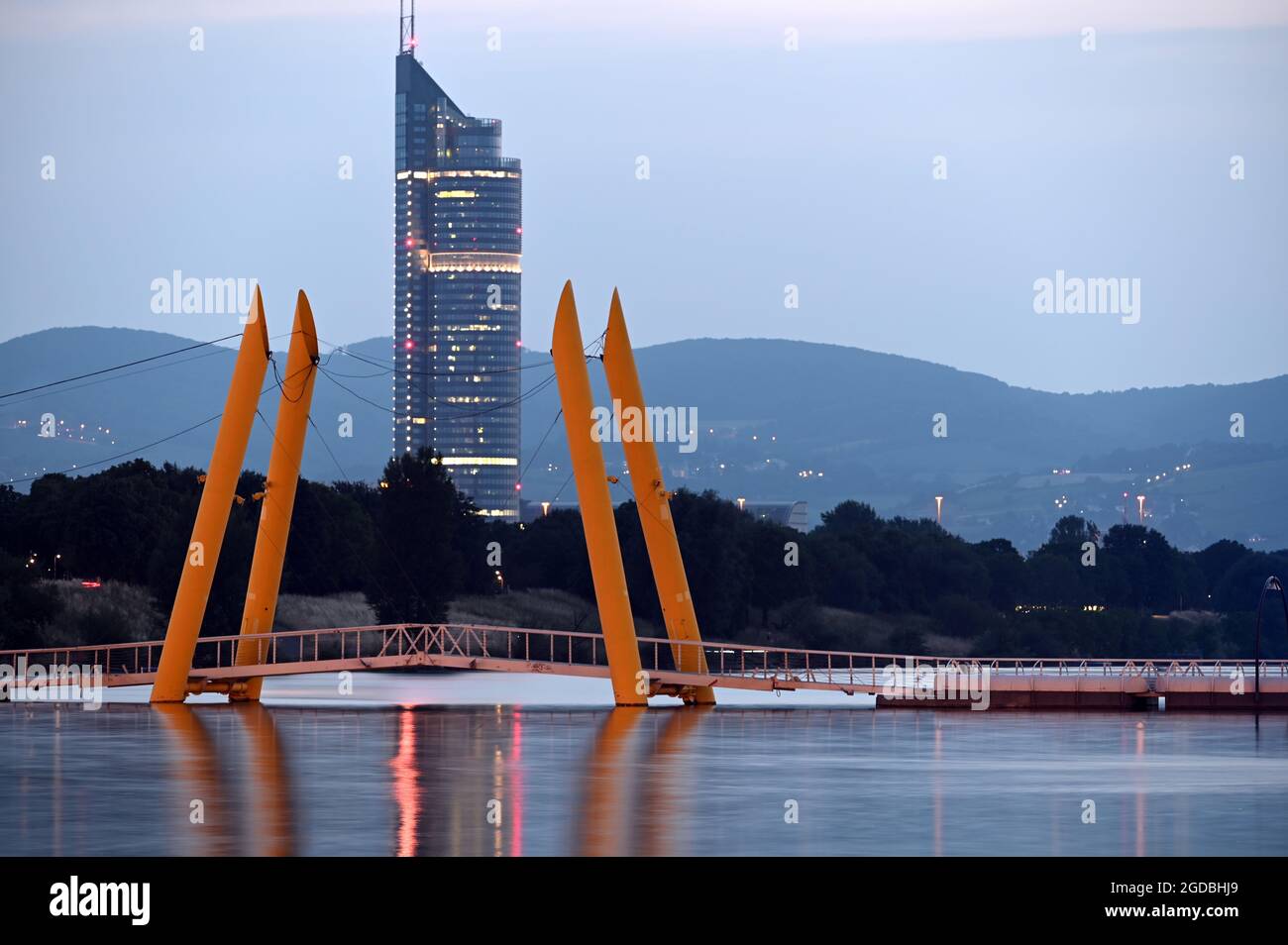 Pedestrian bridge and skyscraper on Danube river at night in Vienna ...