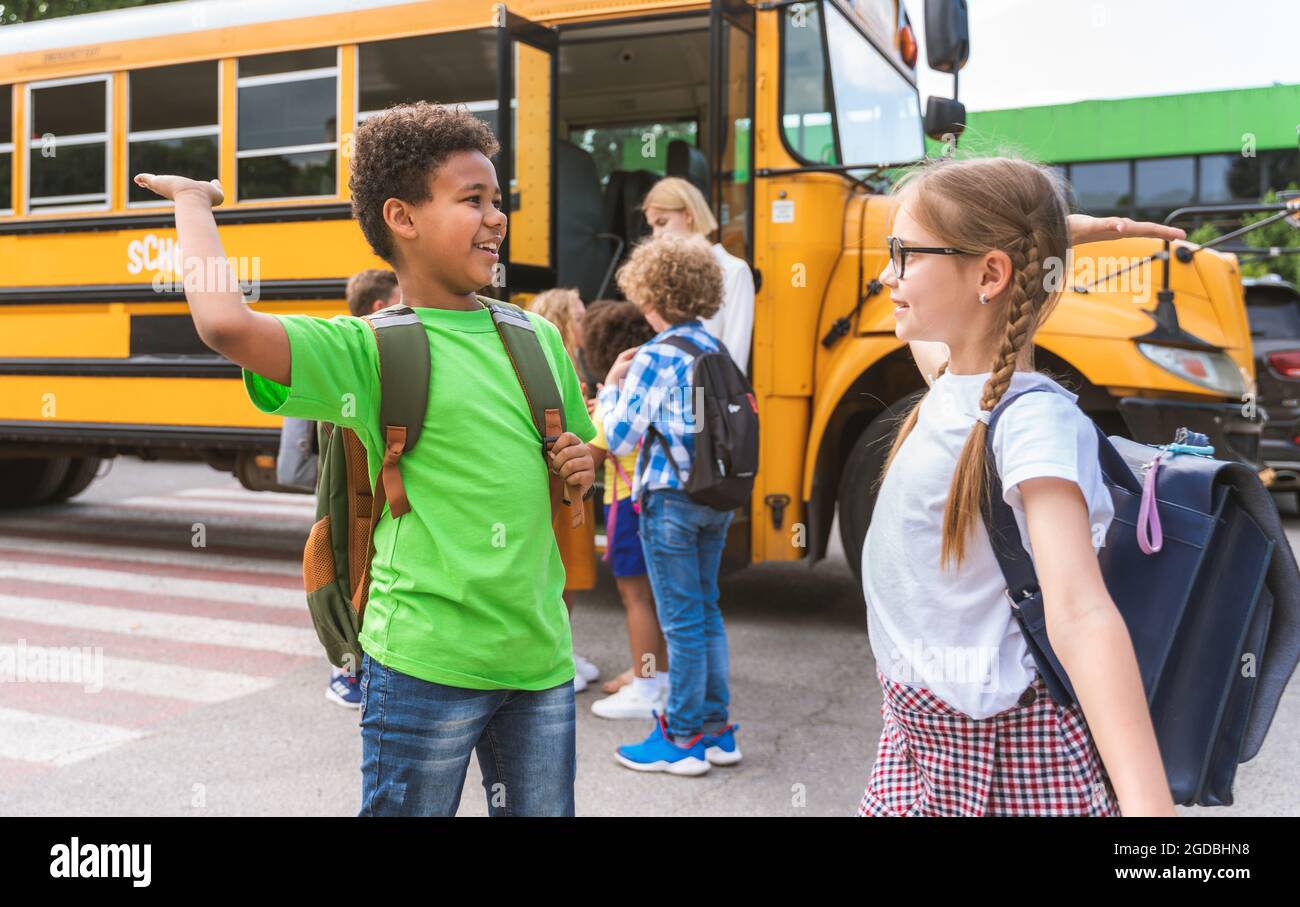 Group of young students attending primary school on a yellow school bus ...