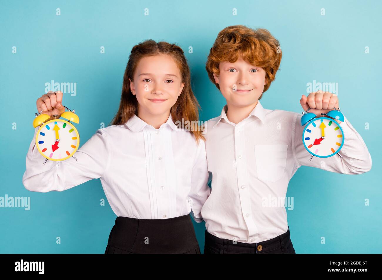 Portrait of two attractive cheerful kids holding childish clock hugging ...