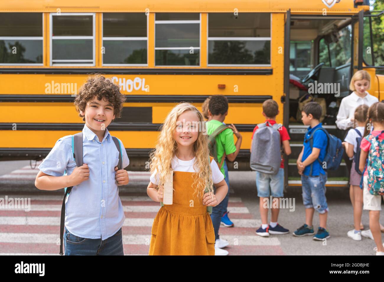 Group of young students attending primary school on a yellow school bus ...