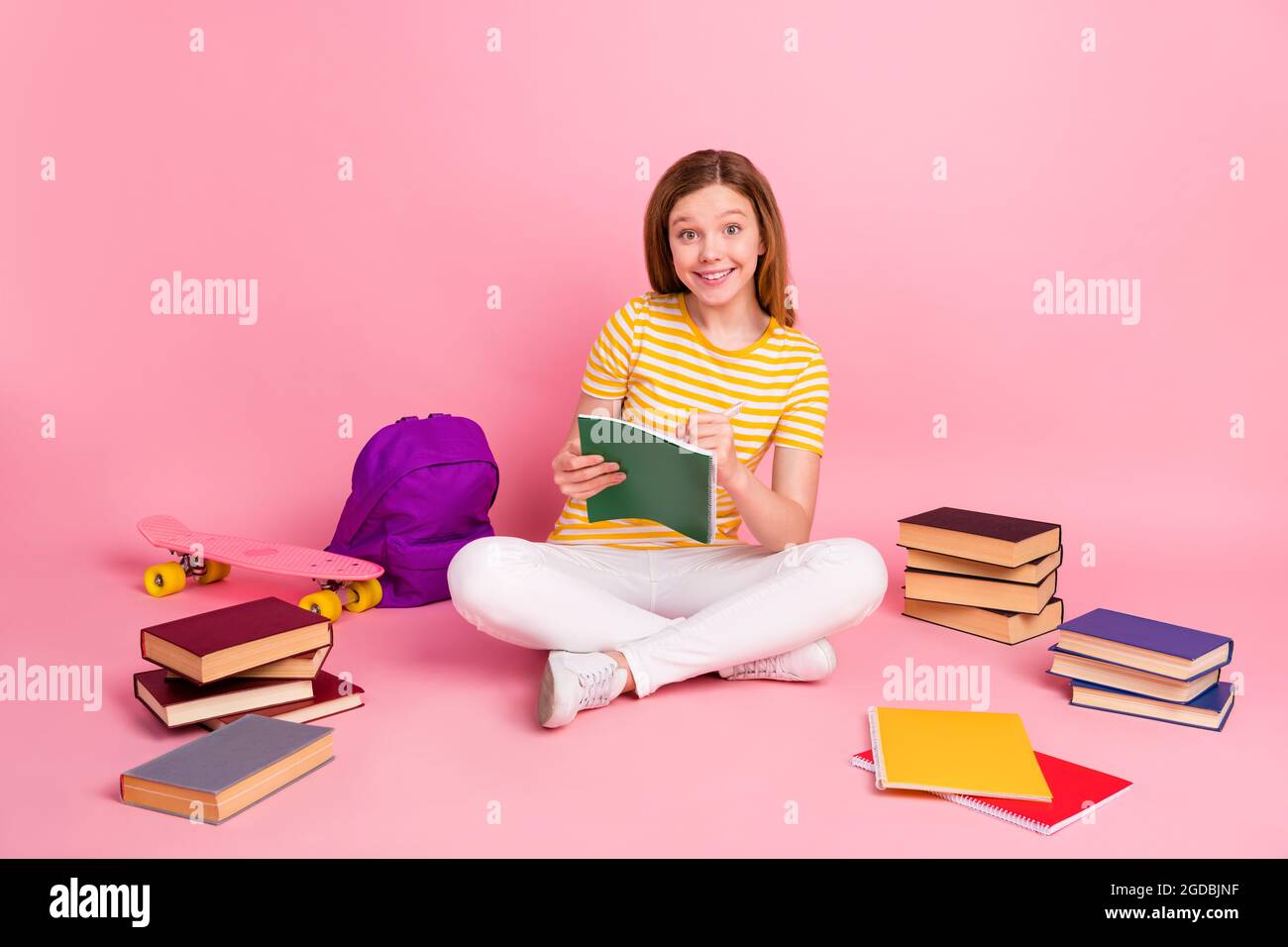 Photo of cheerful girl sit floor write homework wear striped yellow t ...