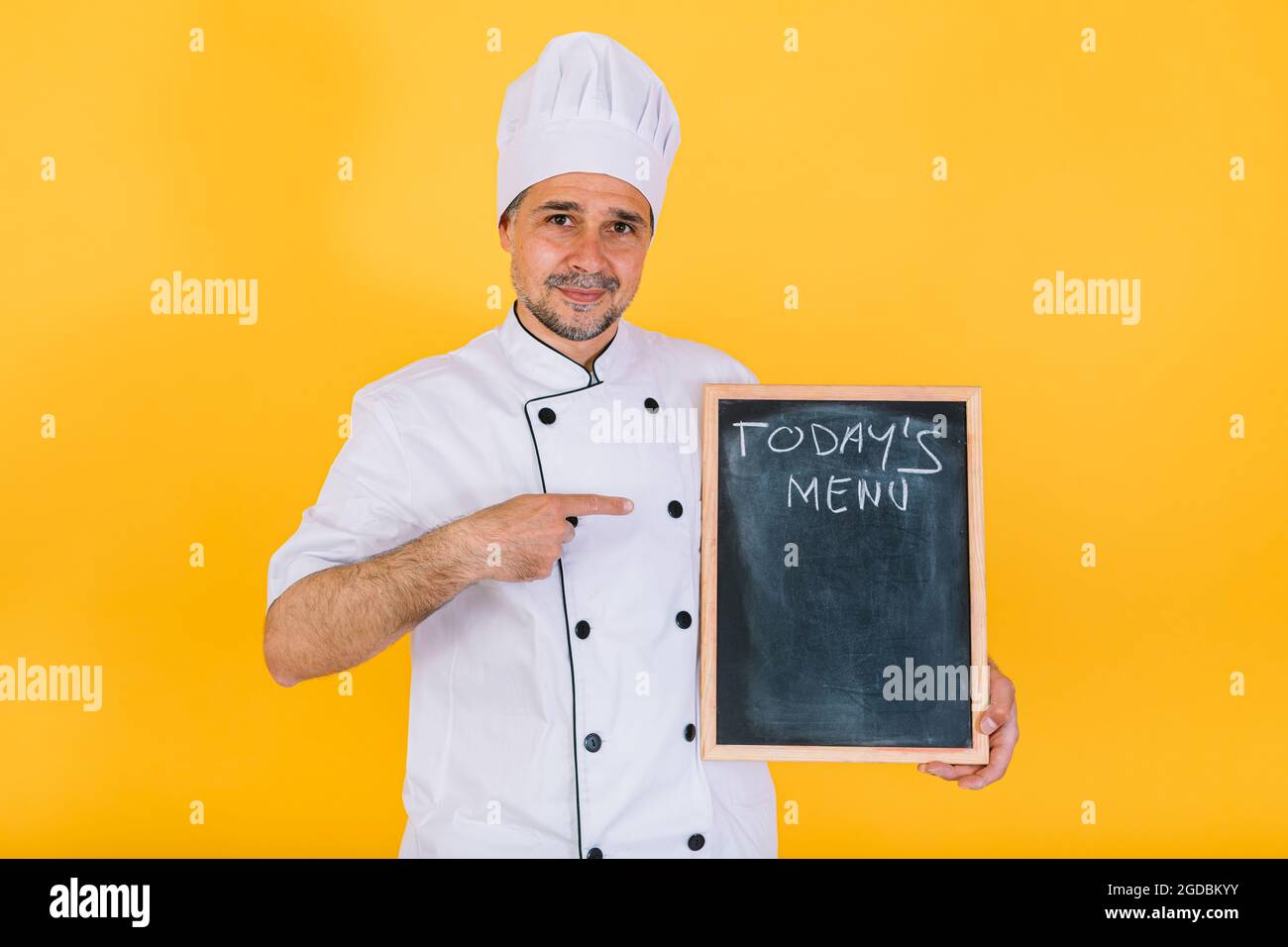 Chef cook wearing white kitchen hat and jacket holding a blackboard ...