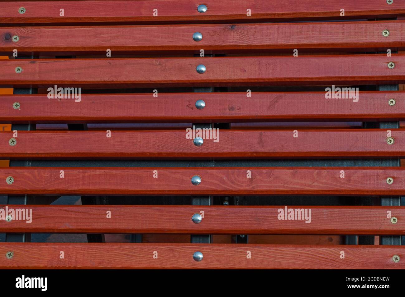 The back of a wooden bench, painted brown, consisting of horizontally ...