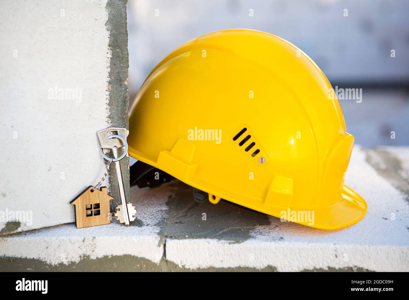 Construction yellow hardhat and key to house on window of housing made ...