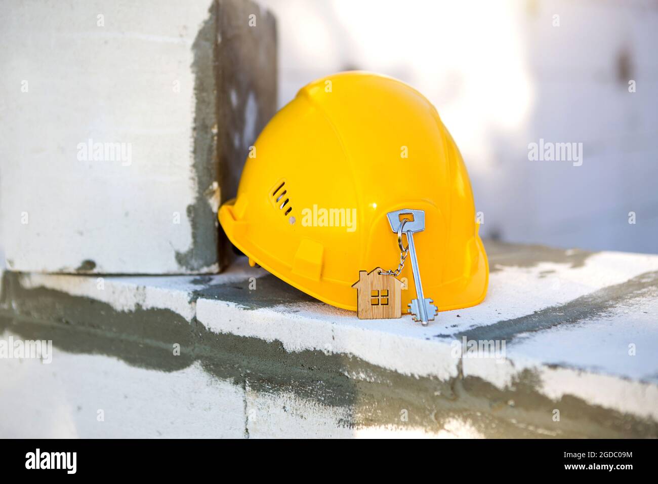 Construction yellow hardhat and key to house on window of housing made ...