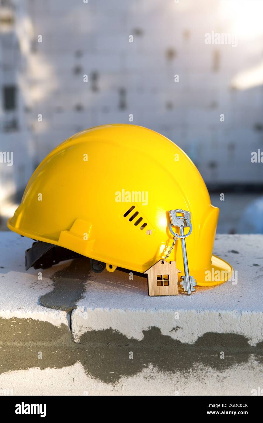 Construction yellow hardhat and key to house on window of housing made ...