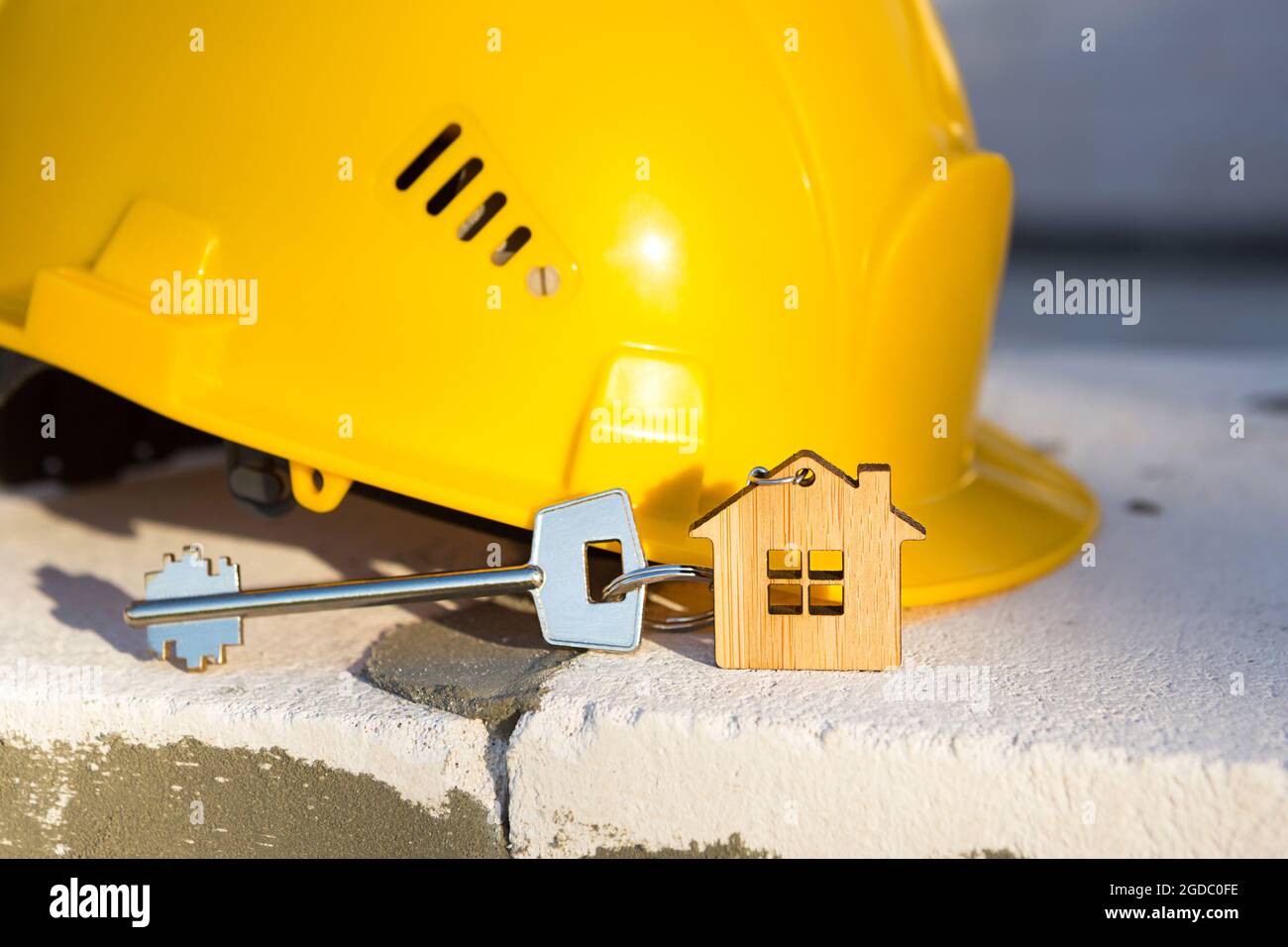 Construction yellow hardhat and key to house on window of housing made ...