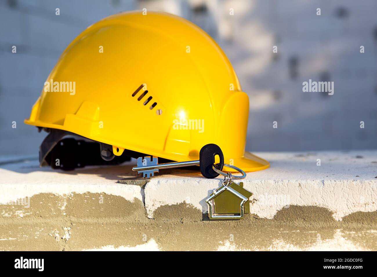 Construction yellow hardhat and key to house on window of housing made ...